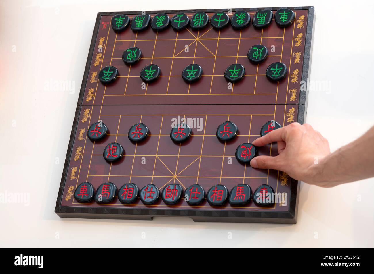 View of a Xiangqi board (Chinese chess) with a hand at the cannon piece ...