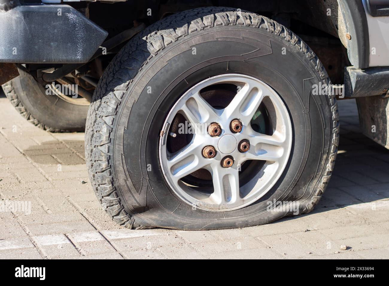 A car with a flat automotive tire on the side of the road, showing its ...