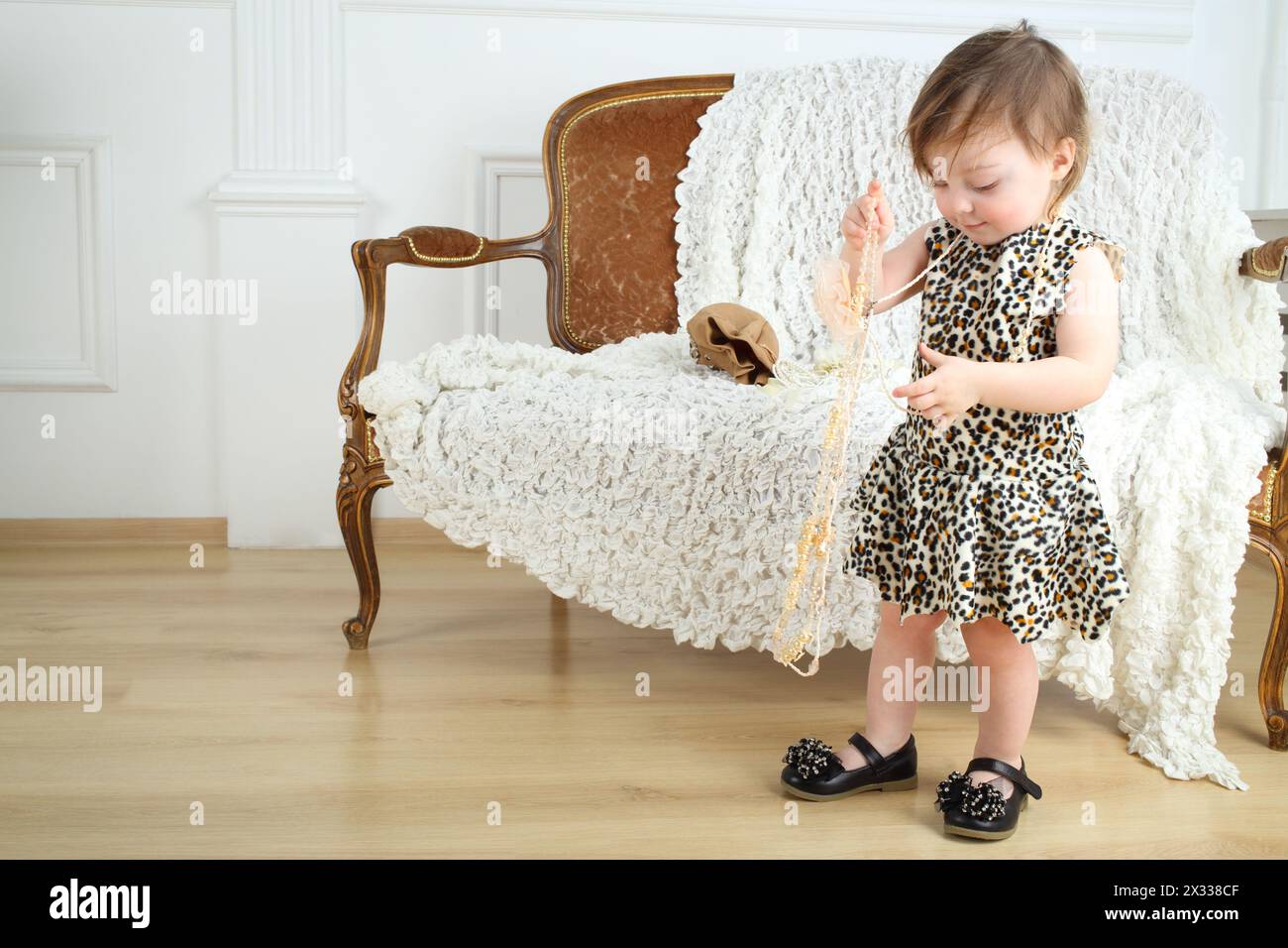 Beautiful little girl in leopard print dress with beads stands near ...