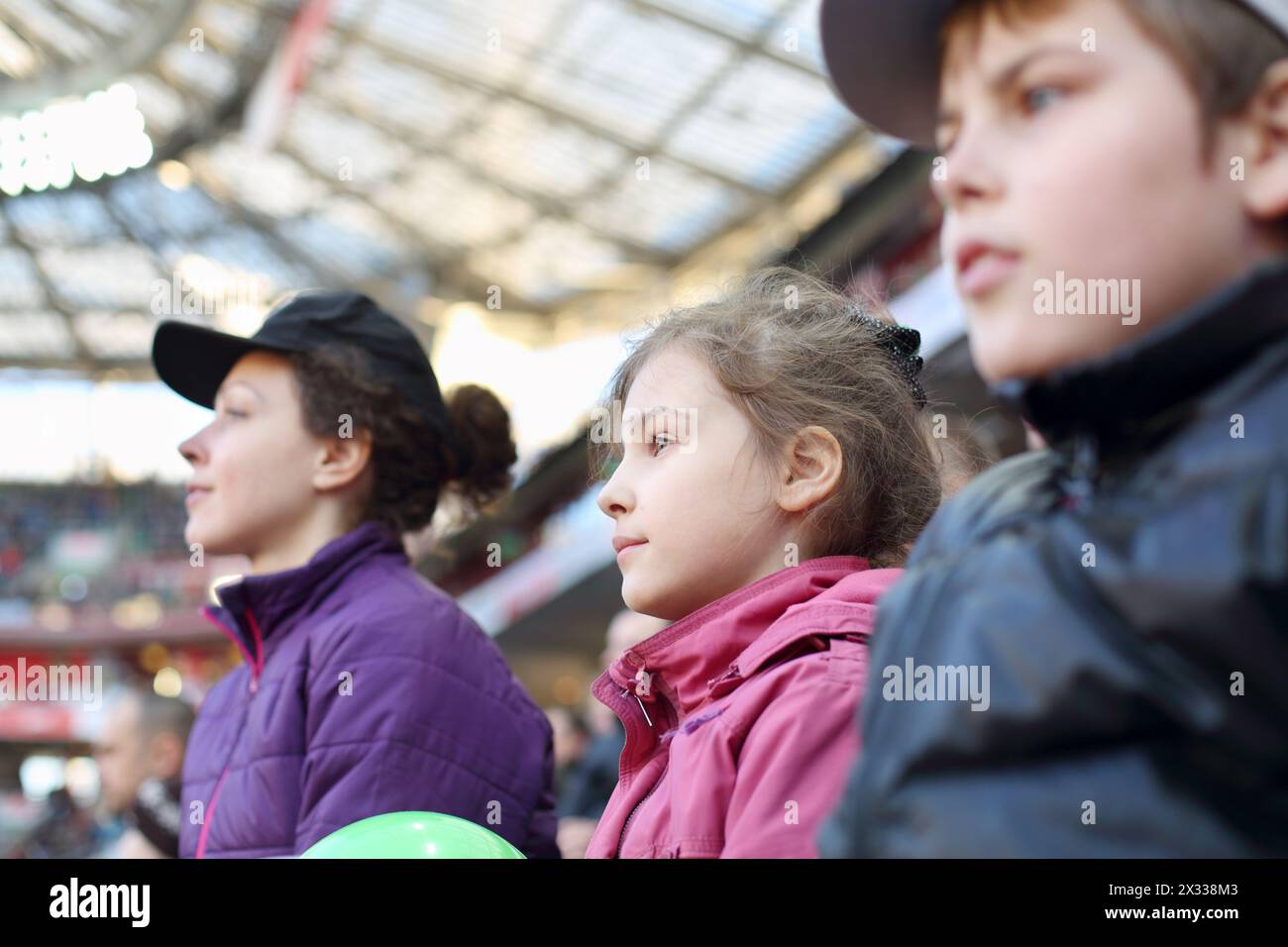 Girl with mother and brother carefully watching game at the stadium ...
