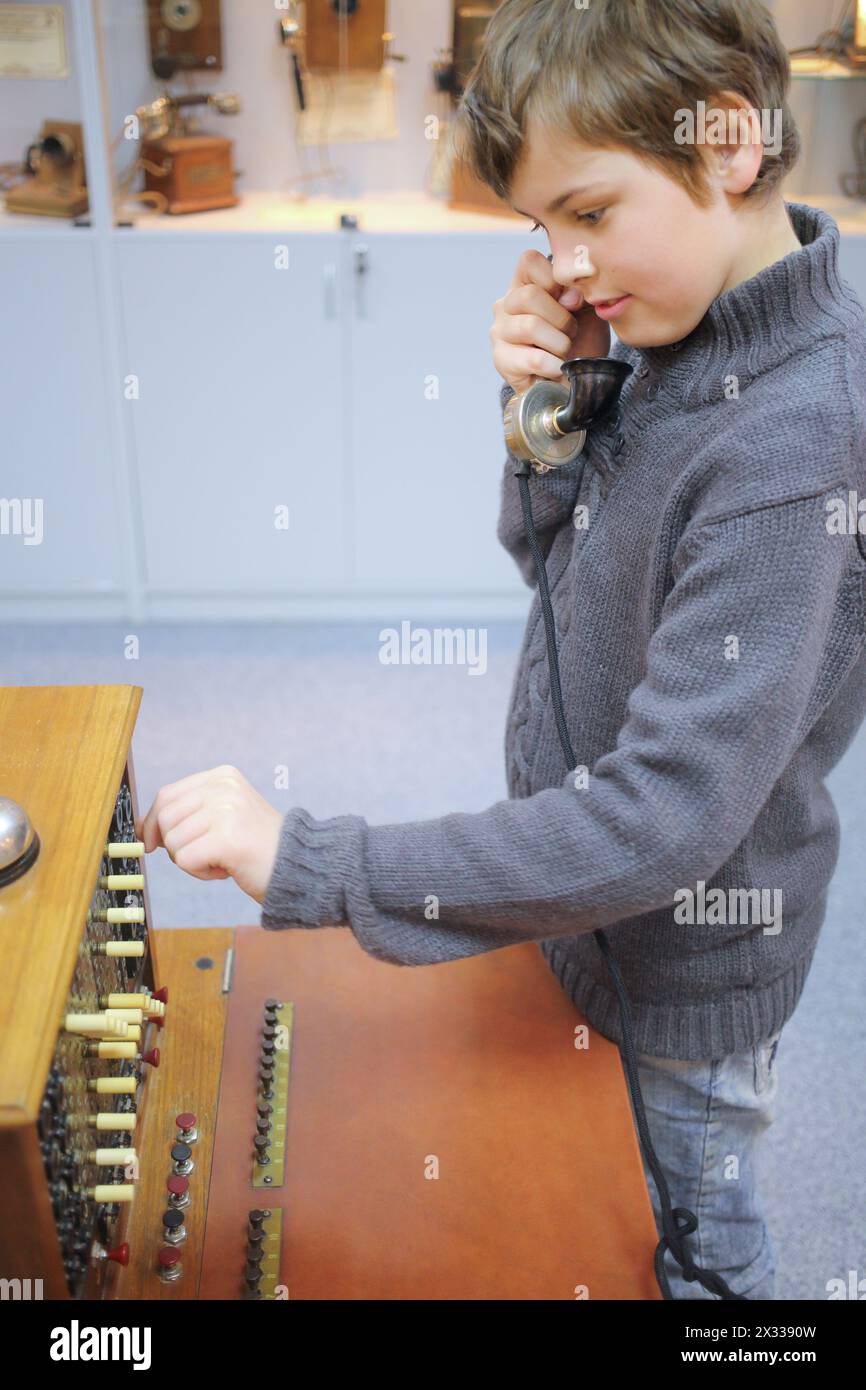 Boy with handset stands about old telephone commutator in the museum ...