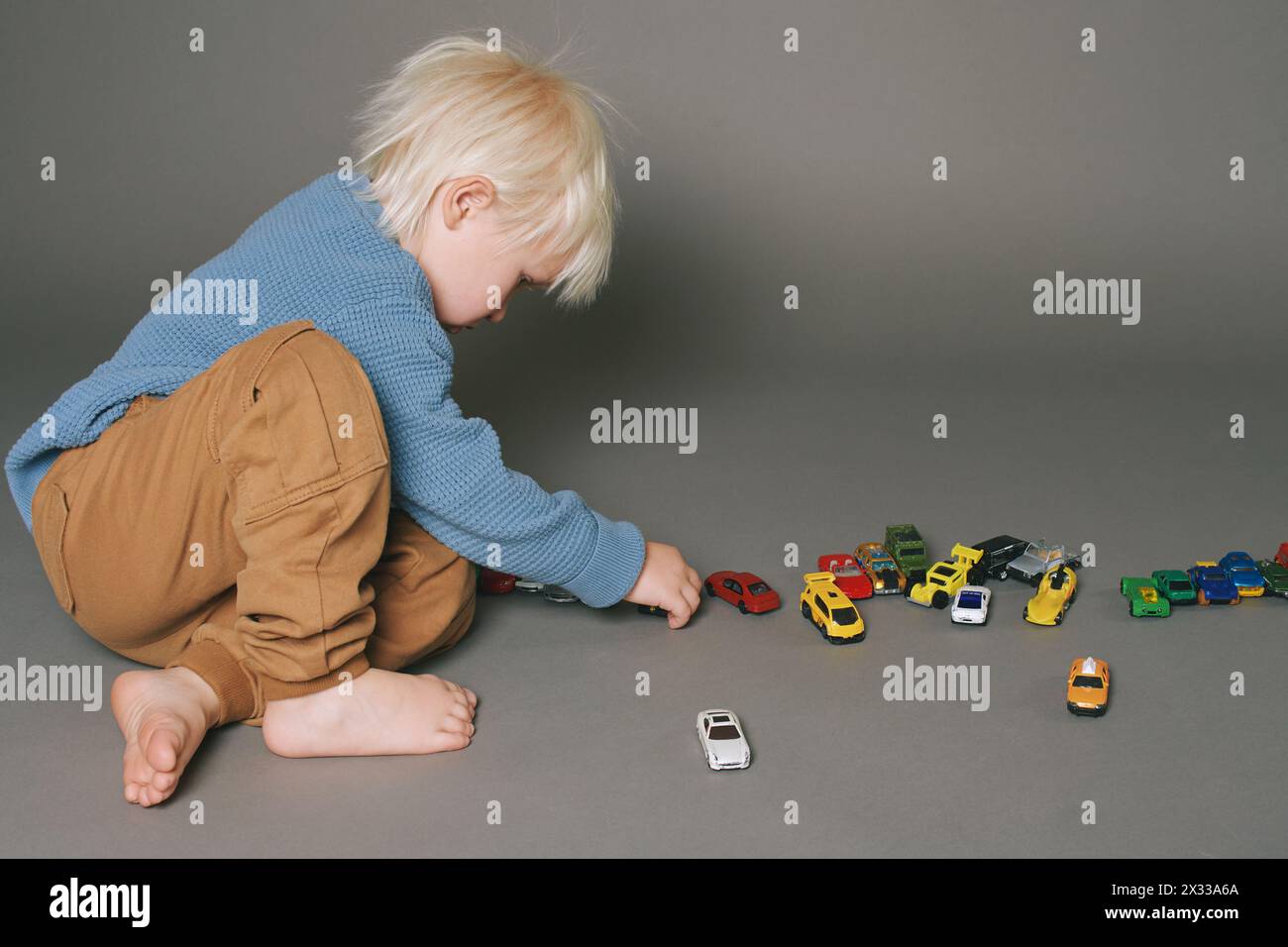 Studio portrait on grey background of adorable little boy playing with ...