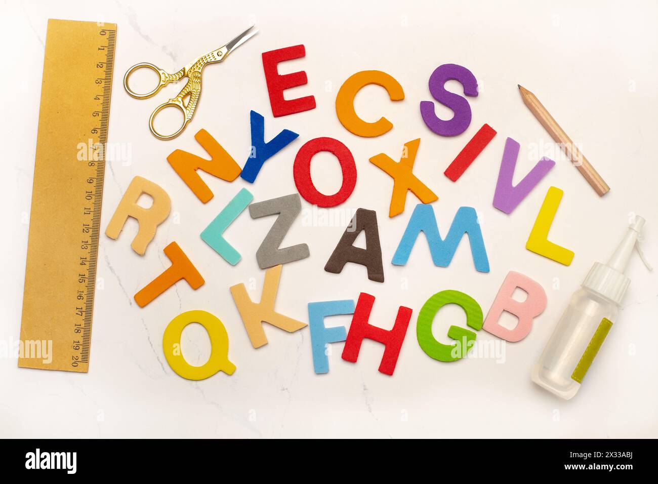 Wooden ruler, scissors, glue, pencil and colored plastic letters on a ...