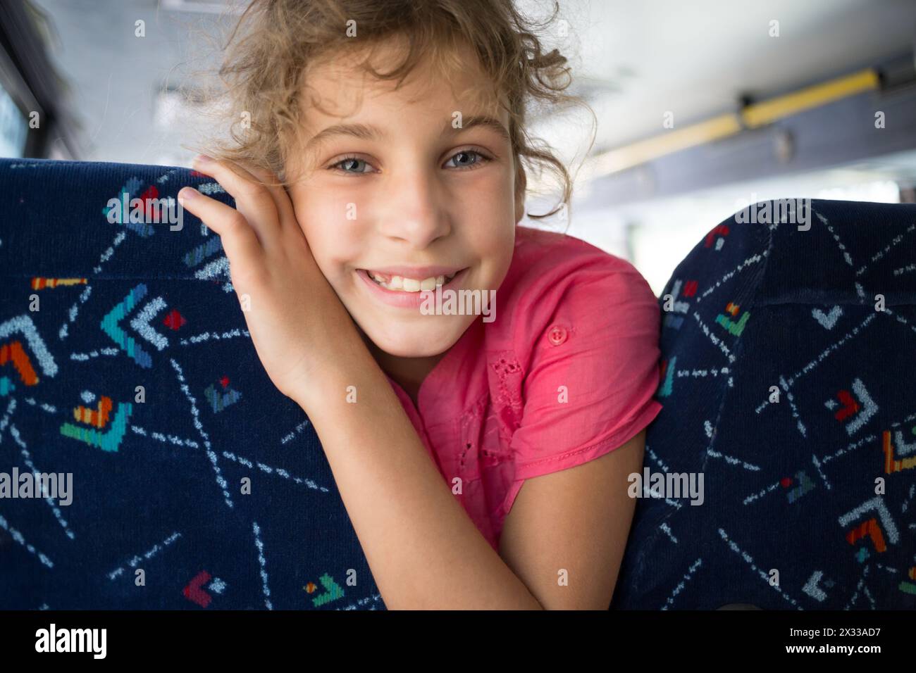 Little girl is sitting between seats in the bus Stock Photo - Alamy