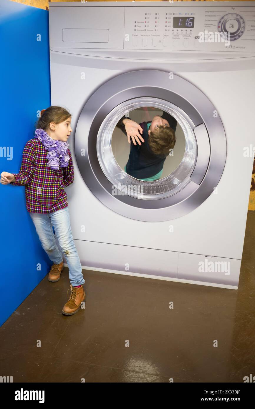 Two children are standing near large washing machine Stock Photo - Alamy