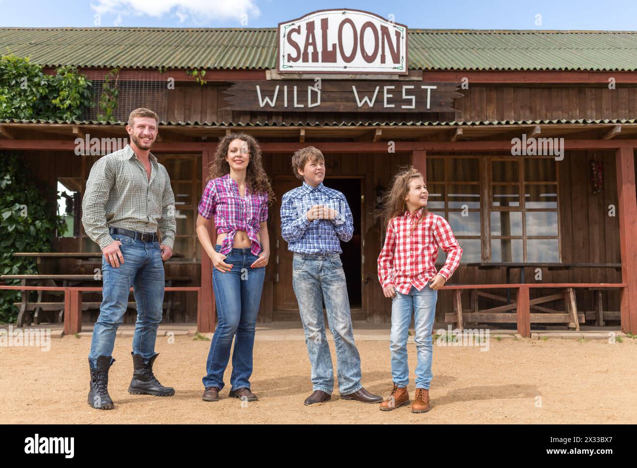 family of four standing on background of wild west saloon Stock Photo ...