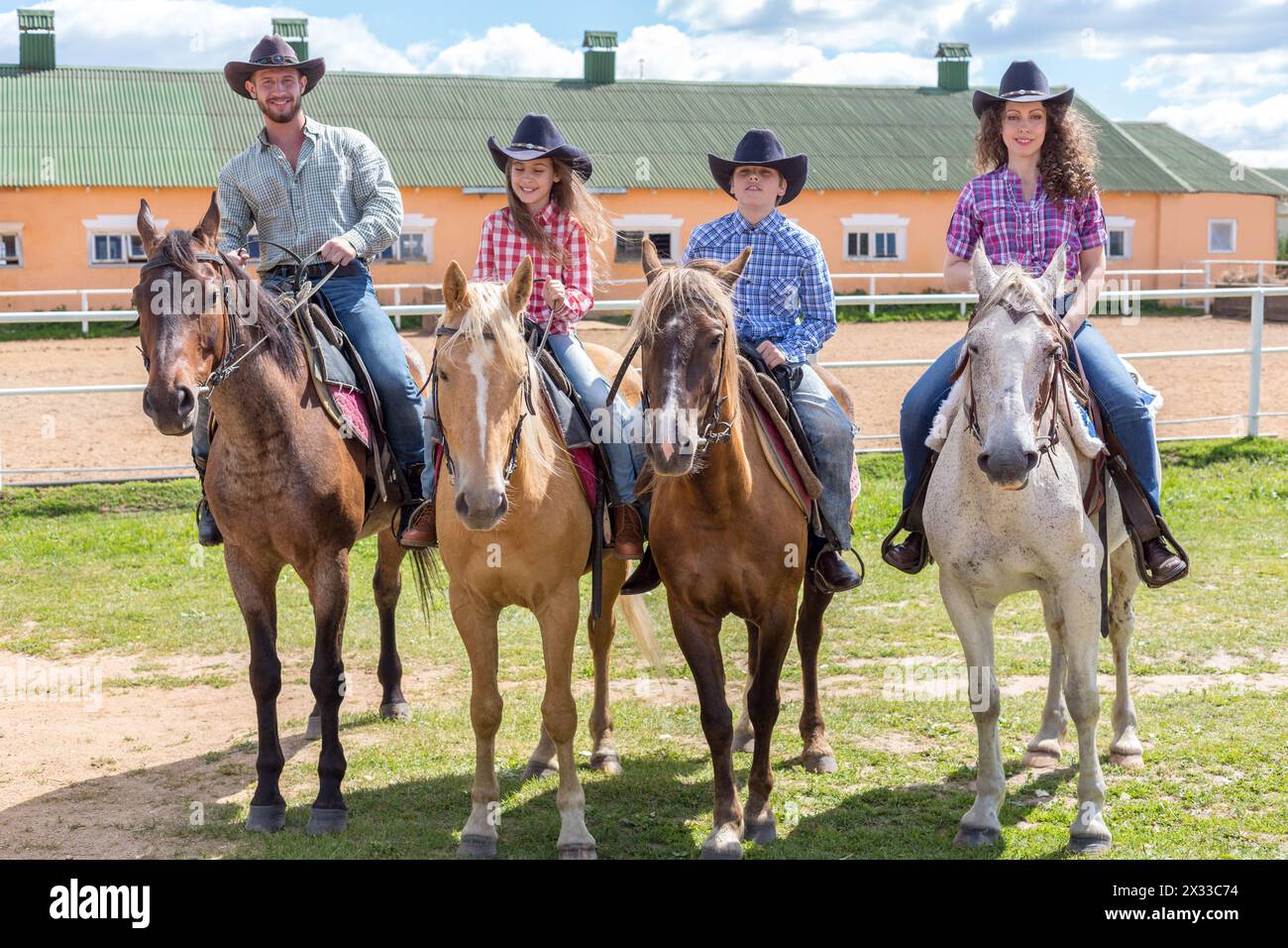 cowboy family of four on horses on background of paddock Stock Photo ...