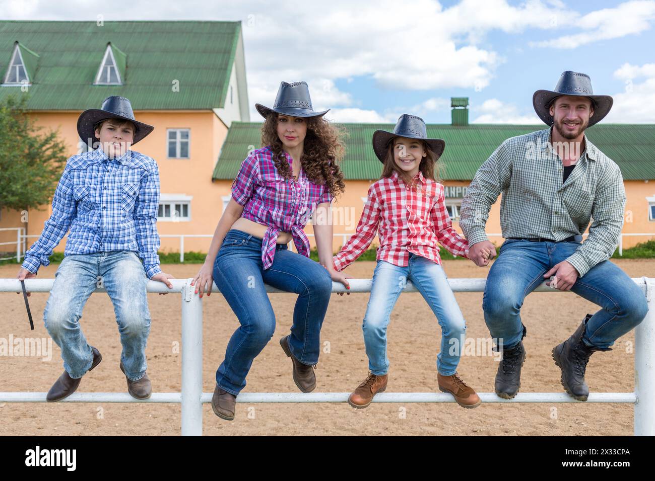 cowboy family sit on the fence of the corral Stock Photo - Alamy