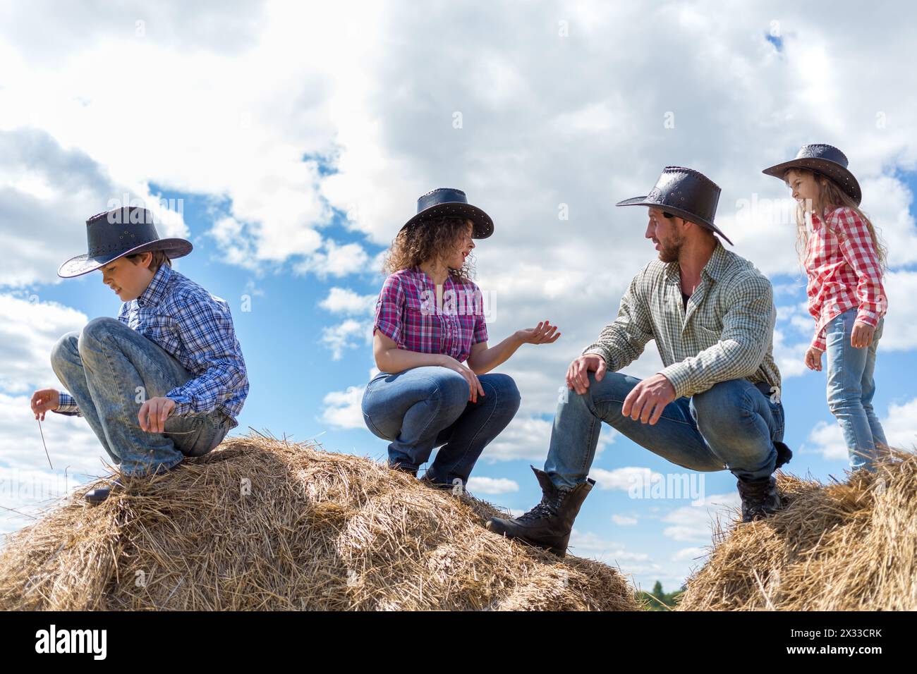 cowboy family of four sitting on haystacks Stock Photo - Alamy
