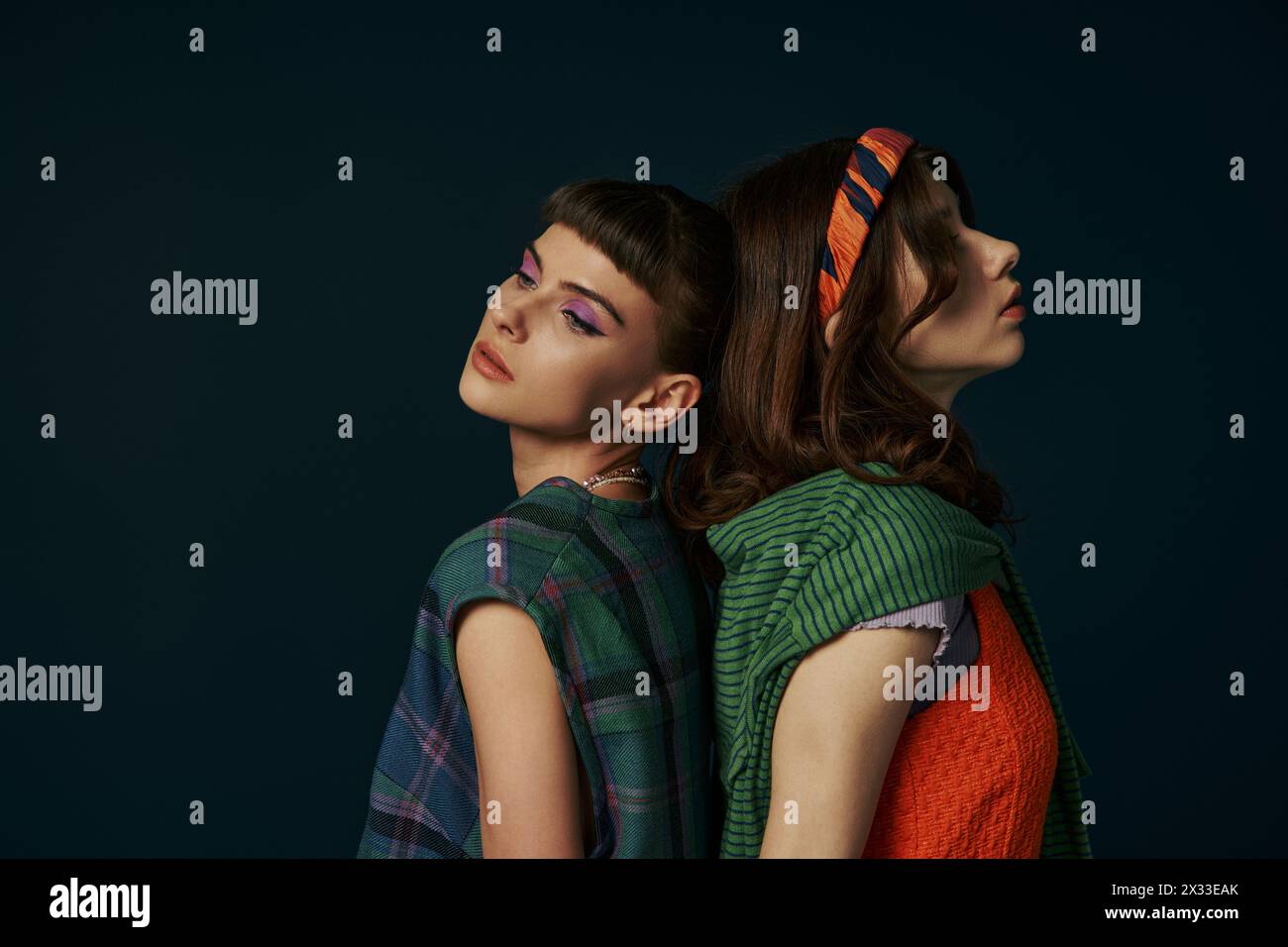 Two women in comfy attire stand side by side against a black backdrop ...