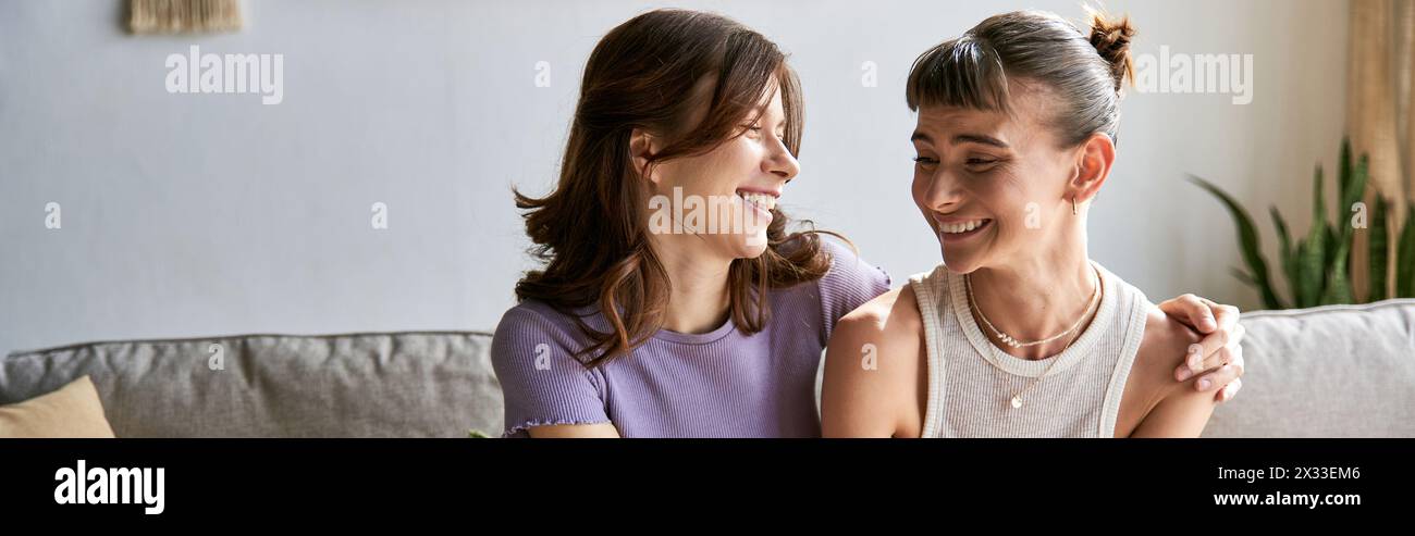 Two women in comfy attire sitting together on a couch Stock Photo - Alamy