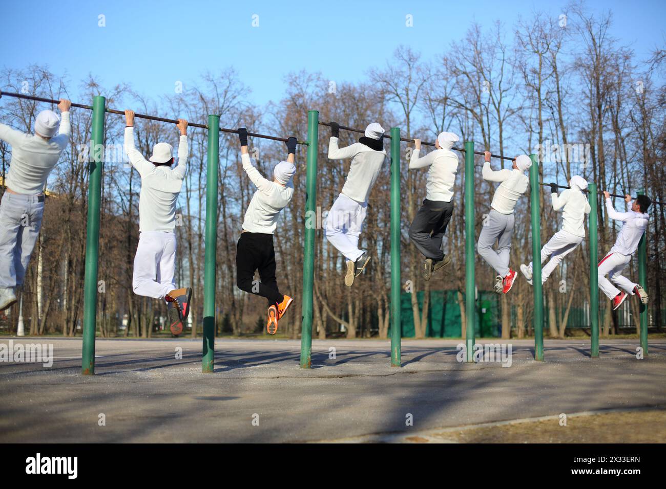 Eight young men coaching on the horizontal bar on the playground, view ...