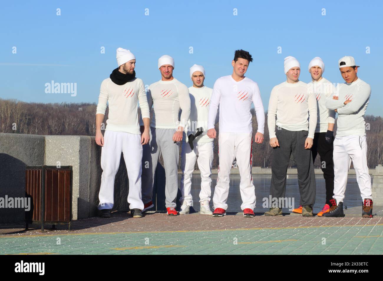 Group of seven young handsome men in white shirts and hats stand in ...