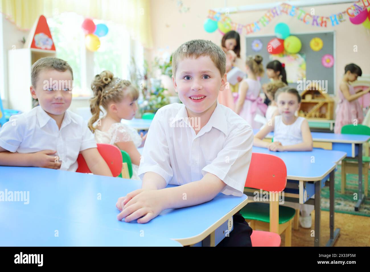 Portrait of a smiling boy in a group with seven children and educator ...