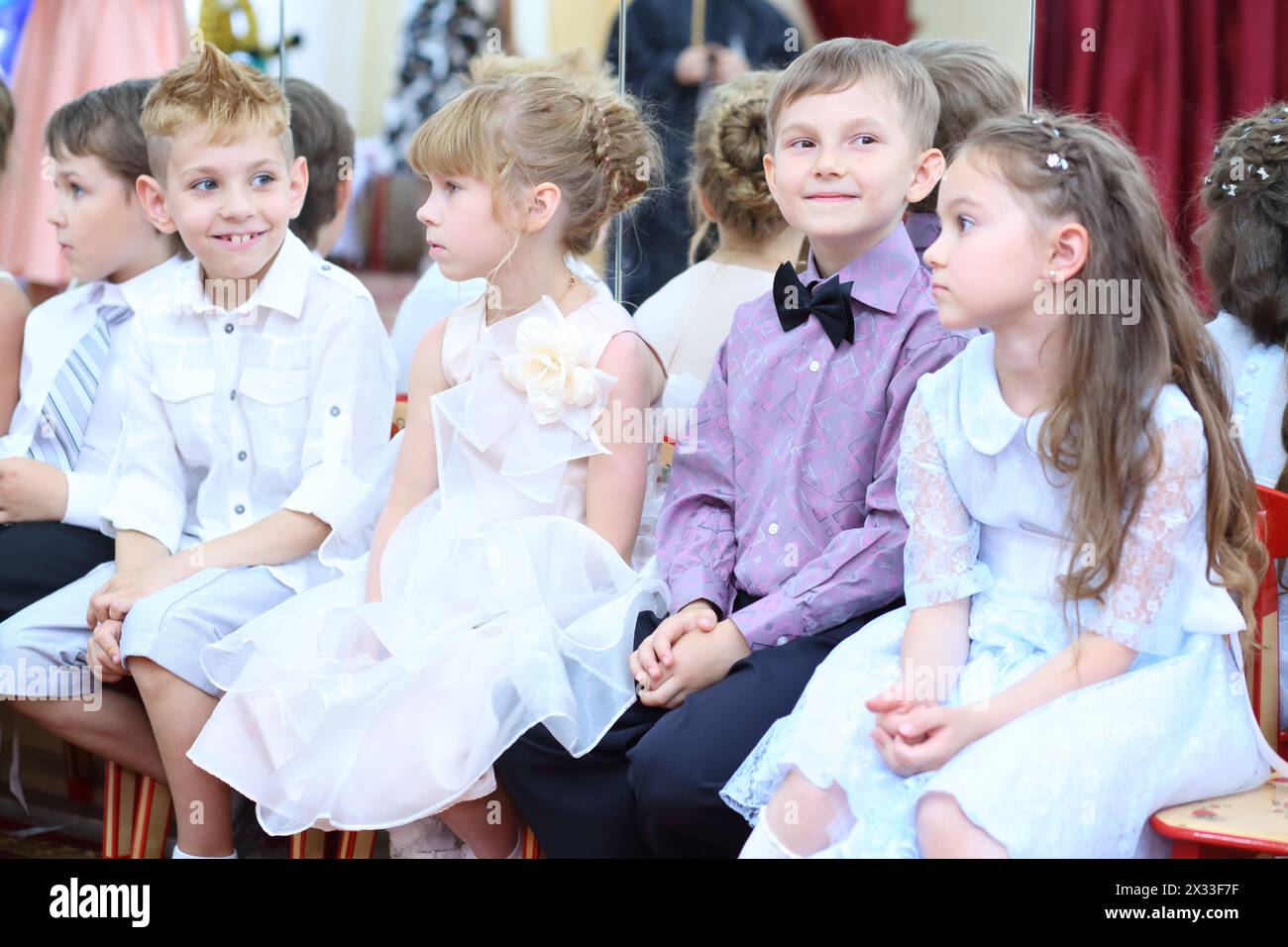 Five elegant small children sit on a chair in the hall at the feast in ...