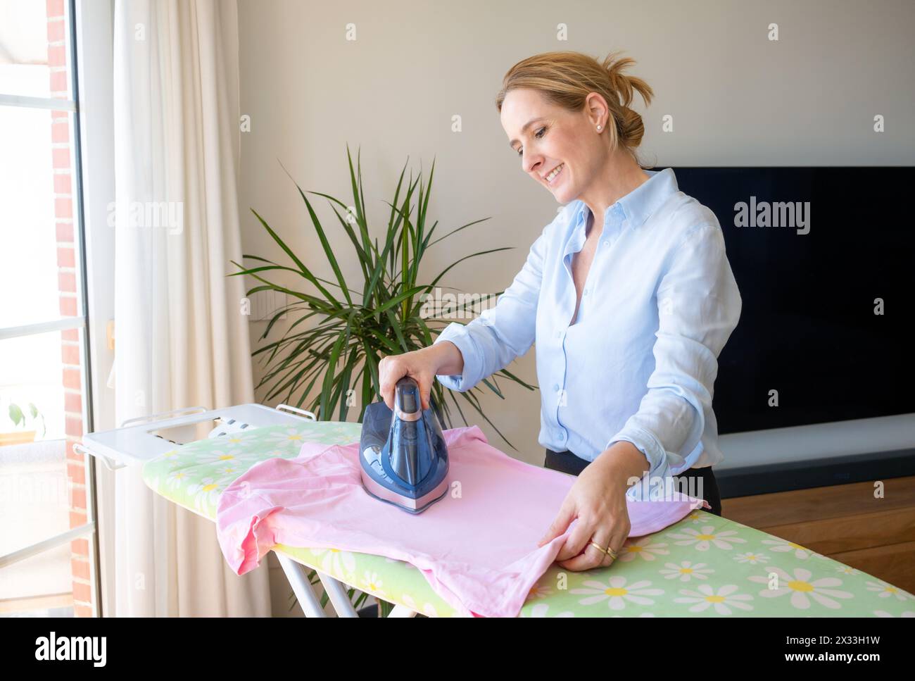 Beautiful young woman is ironing clothes at home Stock Photo - Alamy