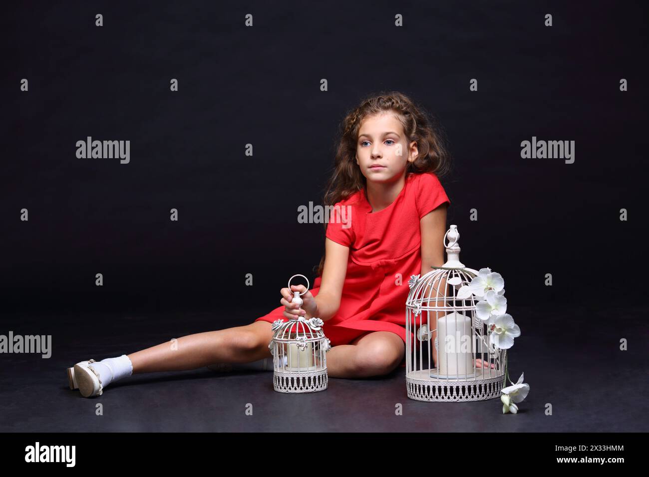 Beautiful girl in red dress sitting on the floor with two white candles ...