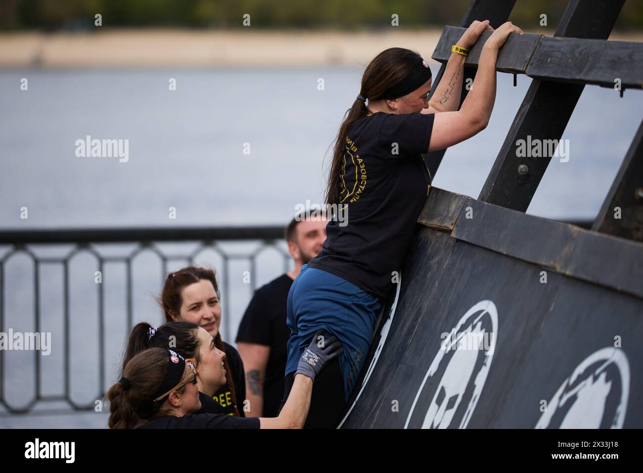 Women help each other to climb the A-shaped wall in a "stairway to ...