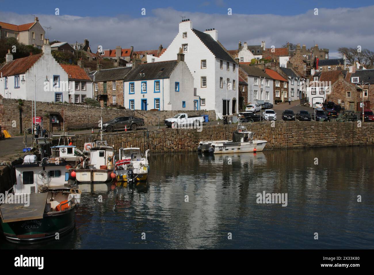 Waterfront buildings reflected in Crail harbour Fife Scotland April ...