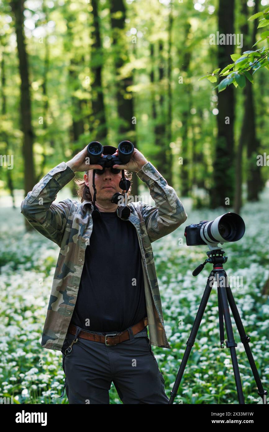 Wildlife photographer is bird watching in forest. Man with binoculars ...
