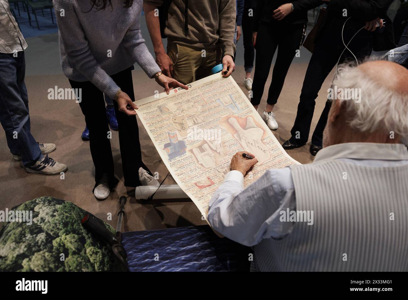 Portrait of Gaetano Pesce (artist) signing a copy of one of his posters ...