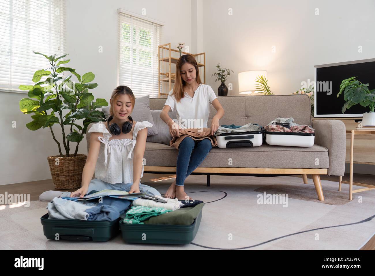 Friendship. Travel together. Two asian young woman friends packing for ...