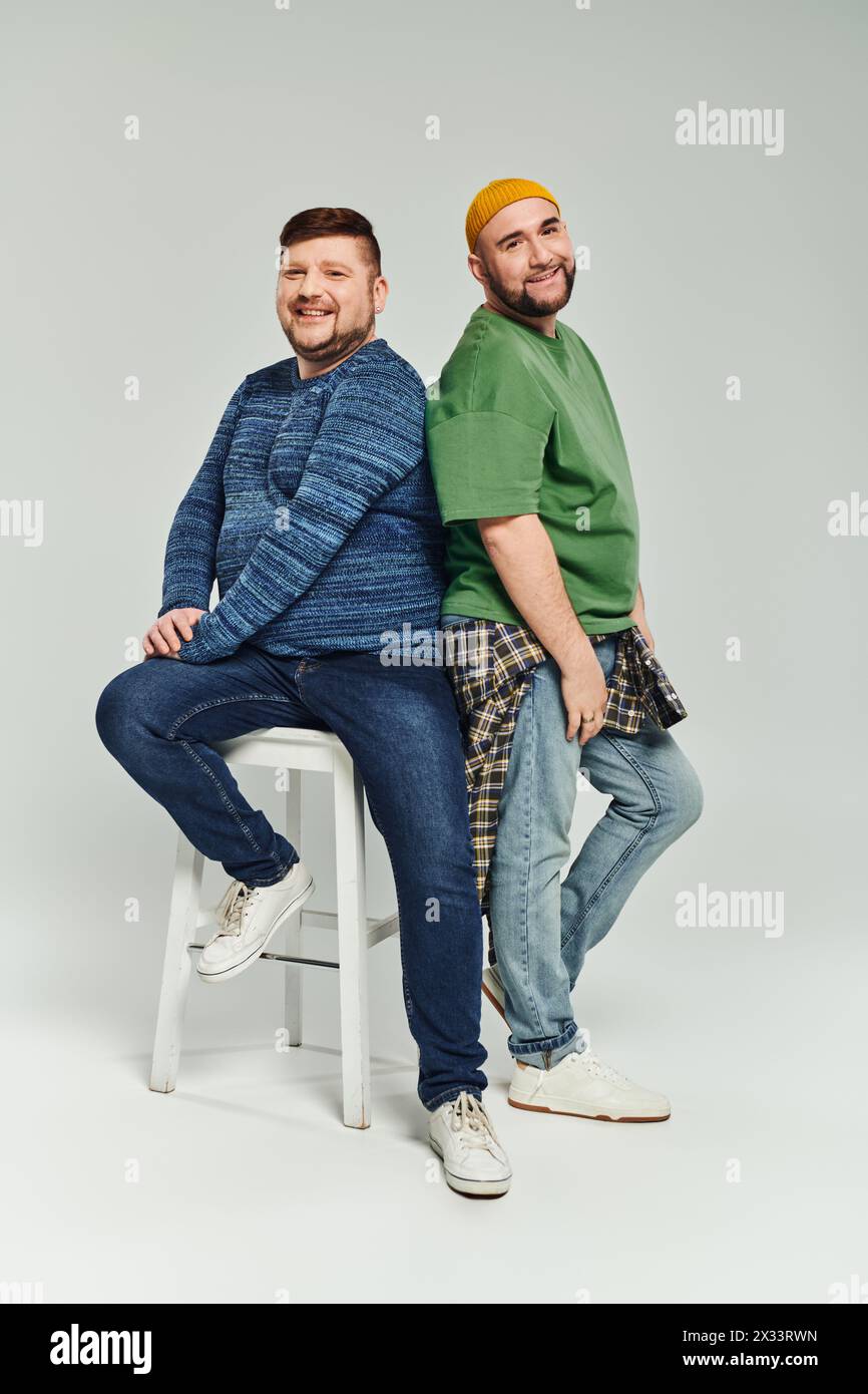 Two men pose together on stool Stock Photo - Alamy