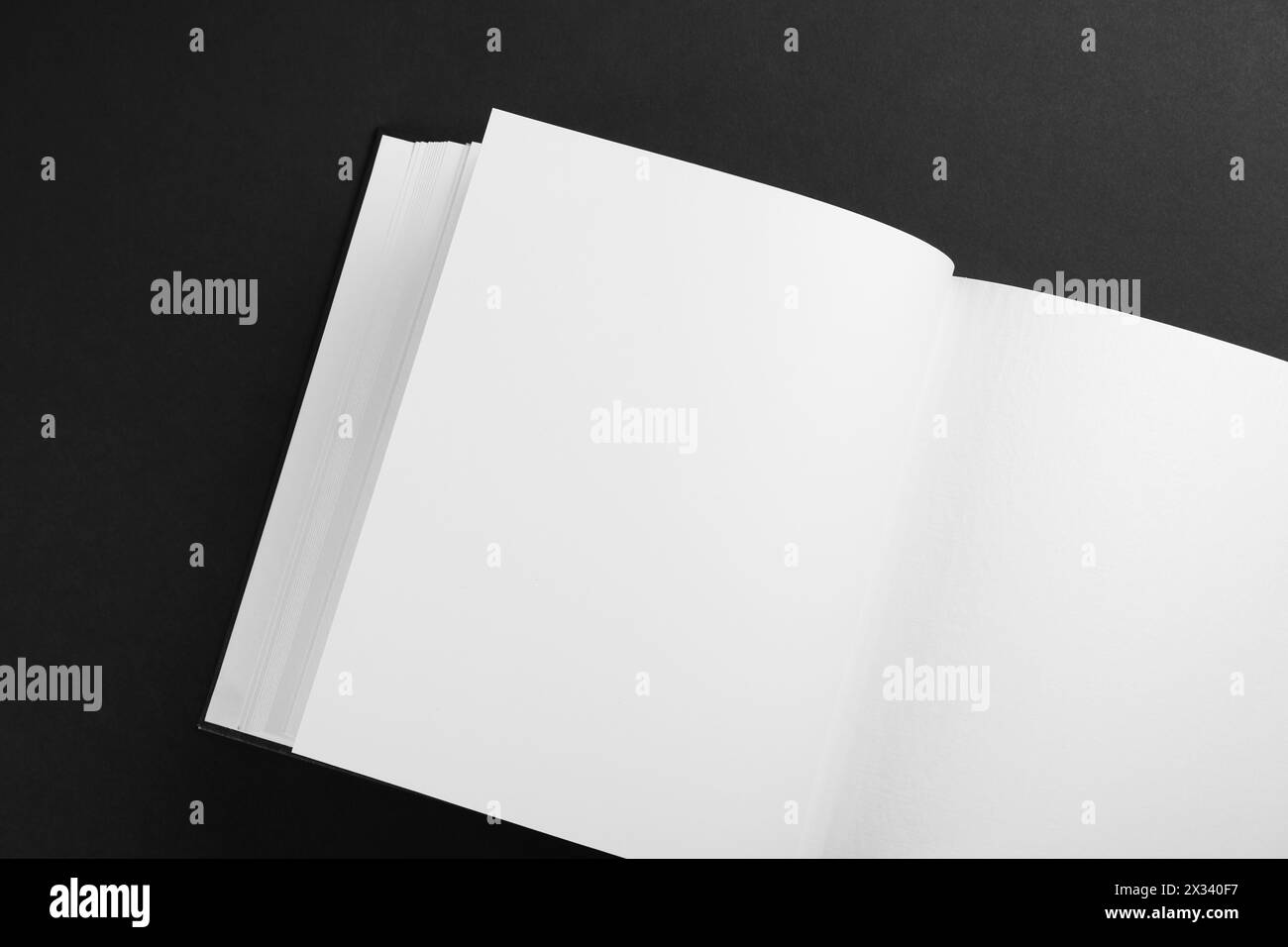 One open photo album on black background, top view. Space for text ...