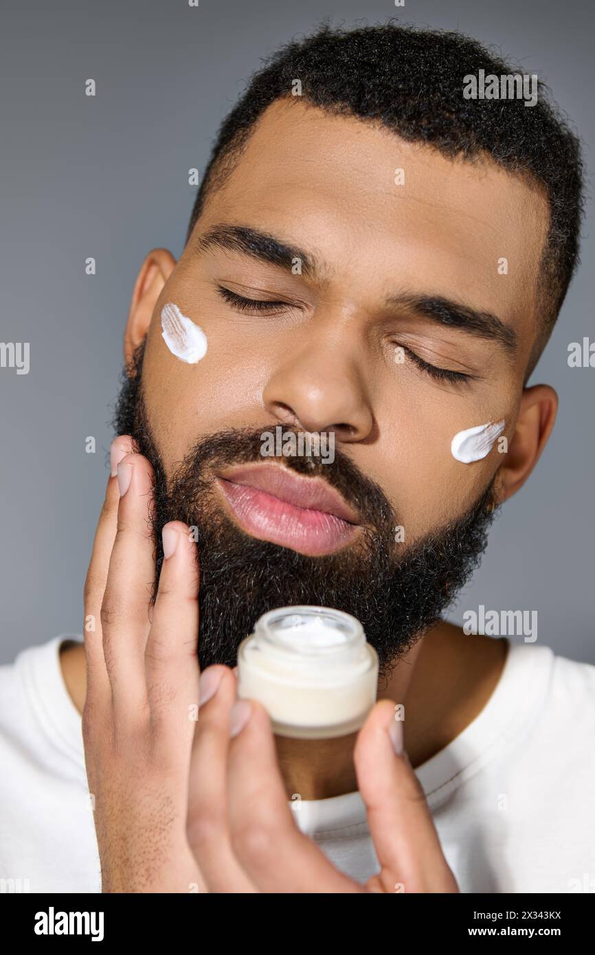 Handsome man with a beard holding a jar of cream for his skin care ...