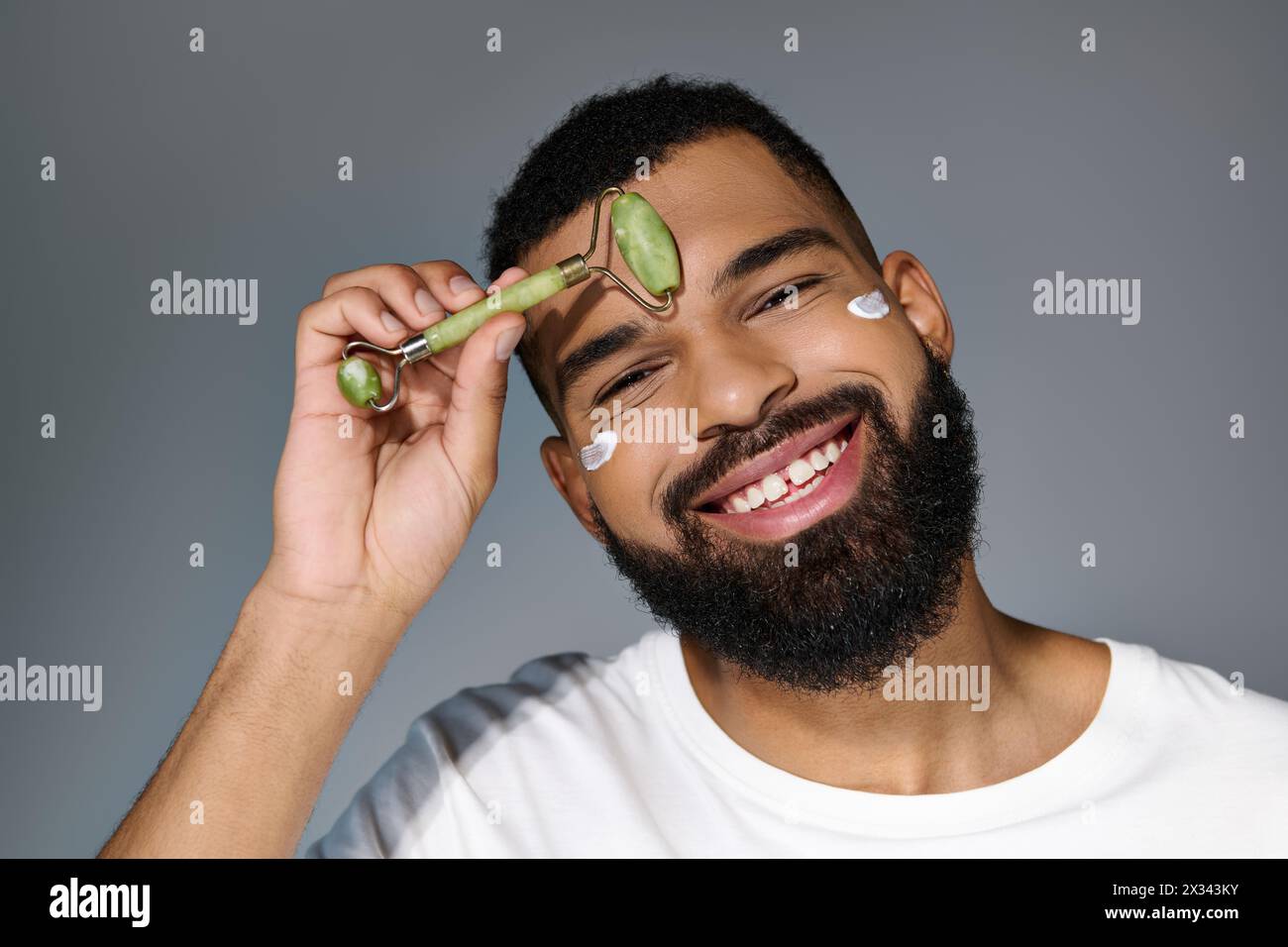 African american bearded man with cream on his face using face roller ...