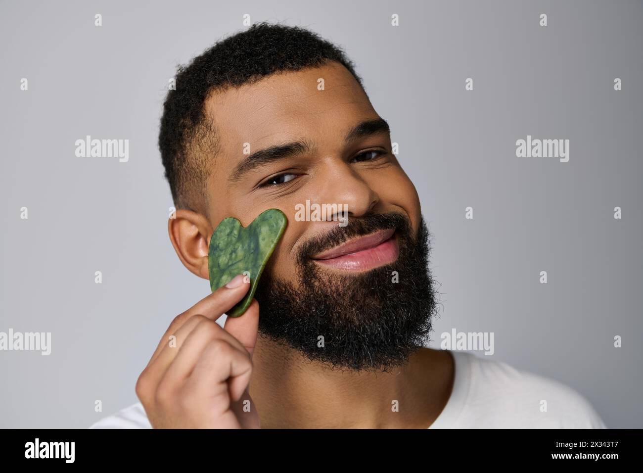 African american young man holds gua sha for skincare routine Stock ... African american young man holds gua sha for skincare routine Stock ...