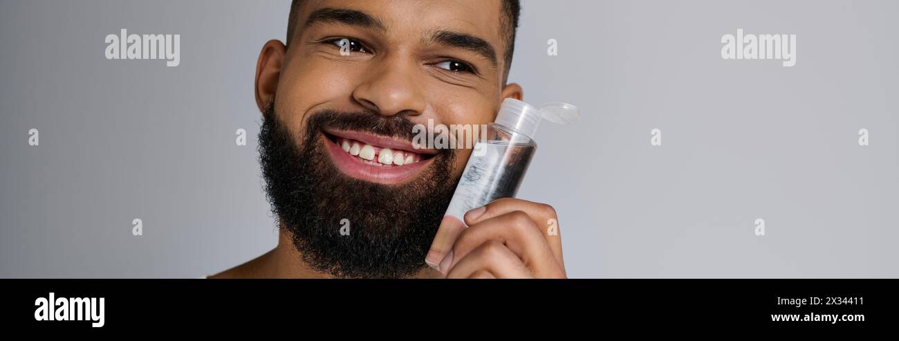 African american handsome man with a beard applying locion on his face ...