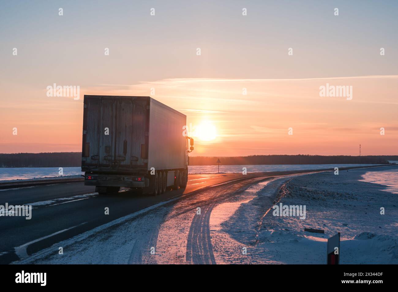 Semi truck driving along a snowy highway at sunset in winter Stock ...