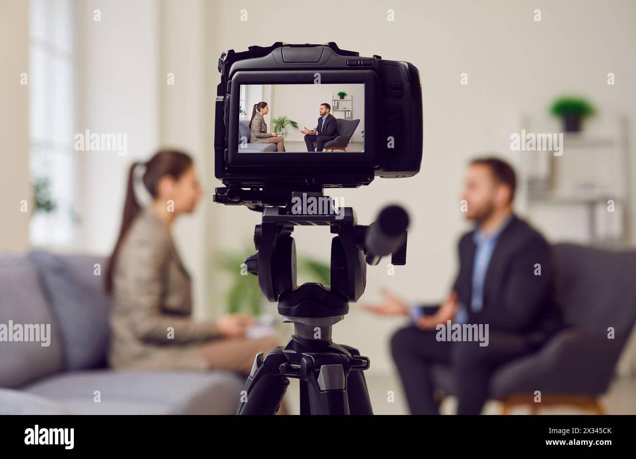 Camera on tripod foreground, businessman giving interview to journalist ...