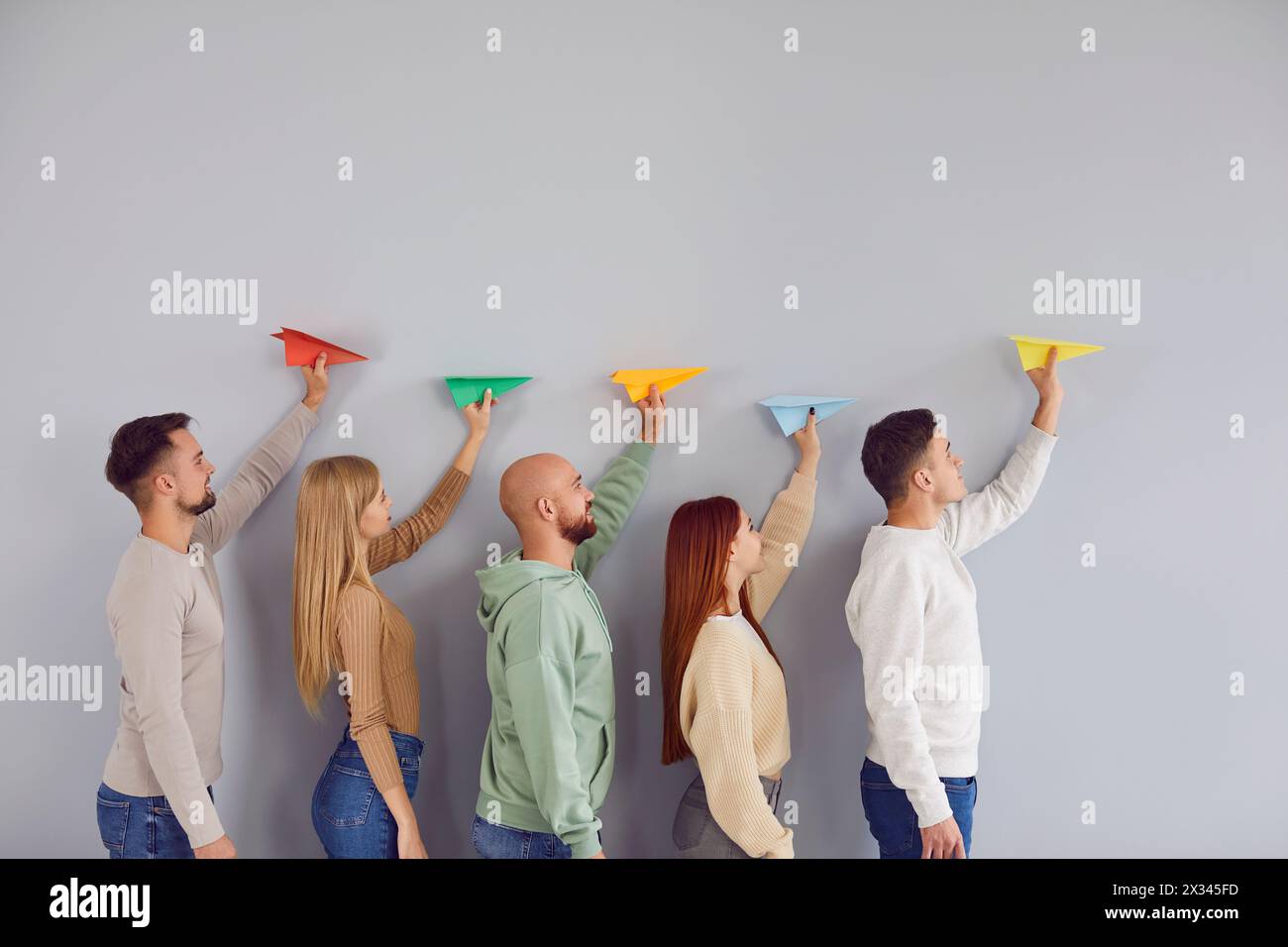 Team holding bright paper origami plane, ready for new start, stage of ...