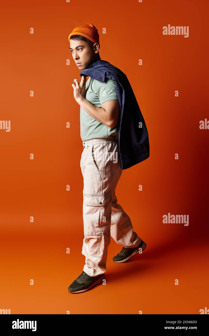 A handsome Asian man in stylish attire carries a backpack on his back ...