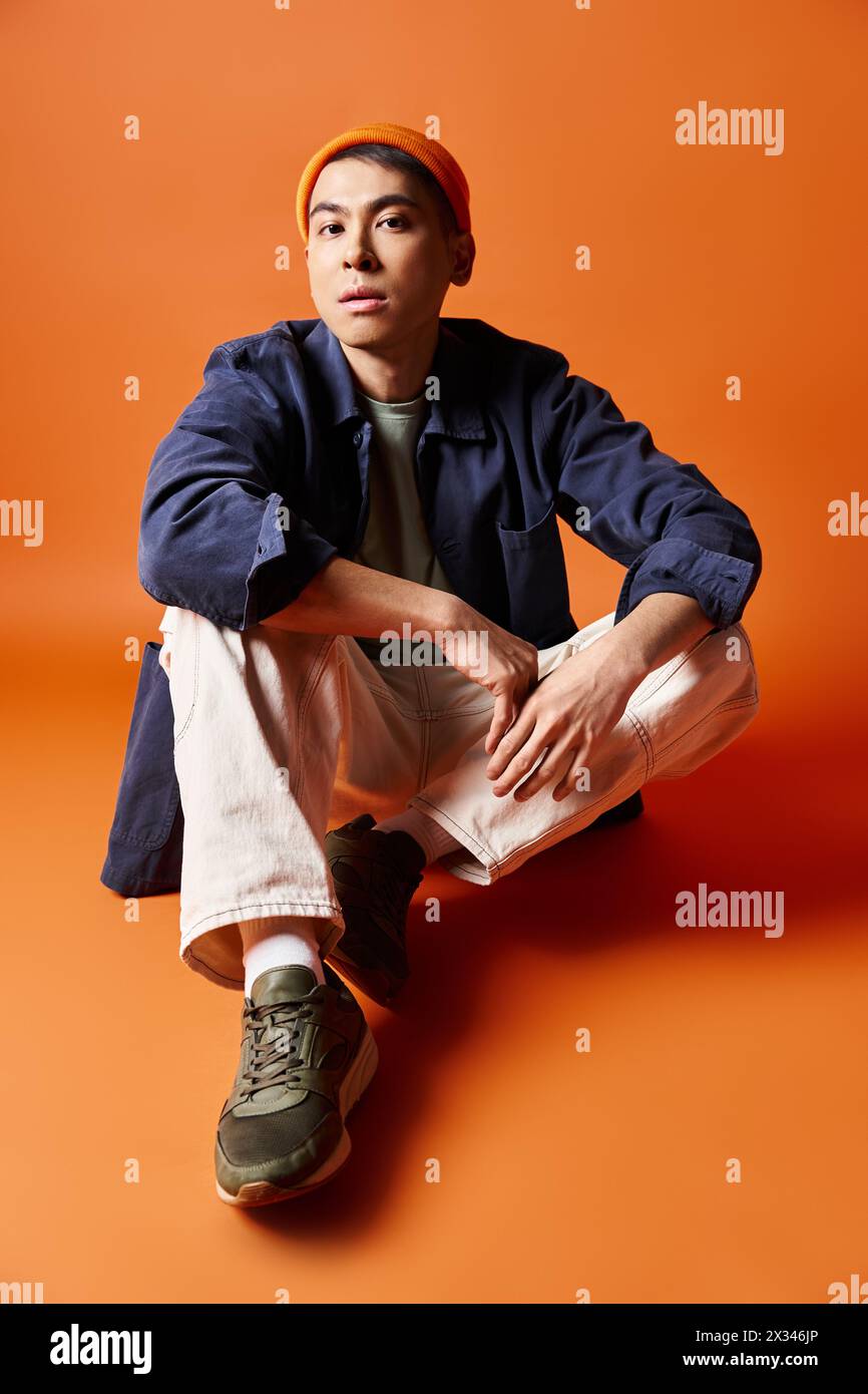 A Handsome Asian Man In Stylish Attire Sits On The Floor With His Legs Crossed In A Pose Of