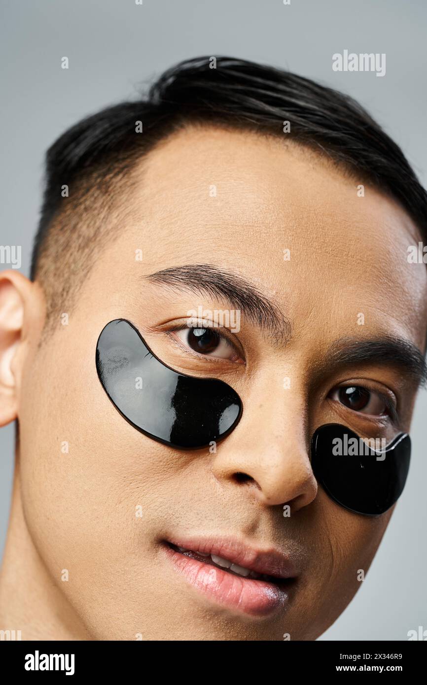 Handsome Asian man with under eye patches during beauty and skincare ...
