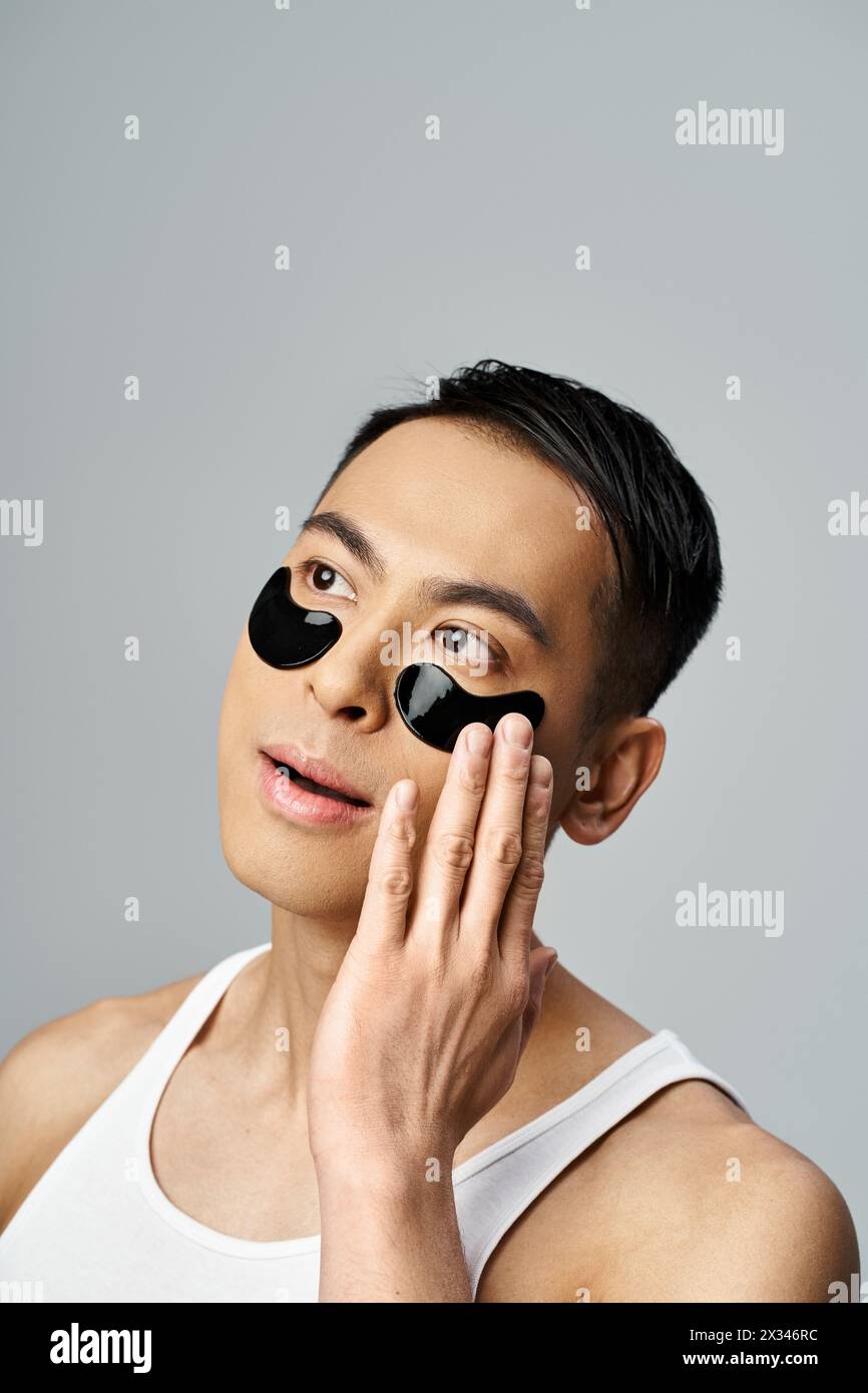 Handsome Asian man with black eye patches, in a beauty and skin care ...