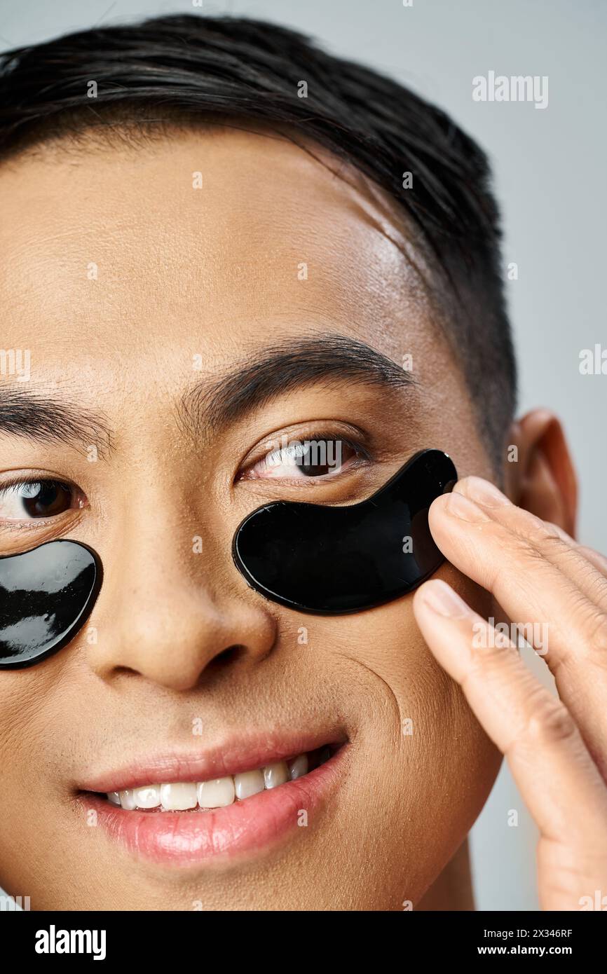 Handsome Asian man applies black eye patches for his skincare routine ...