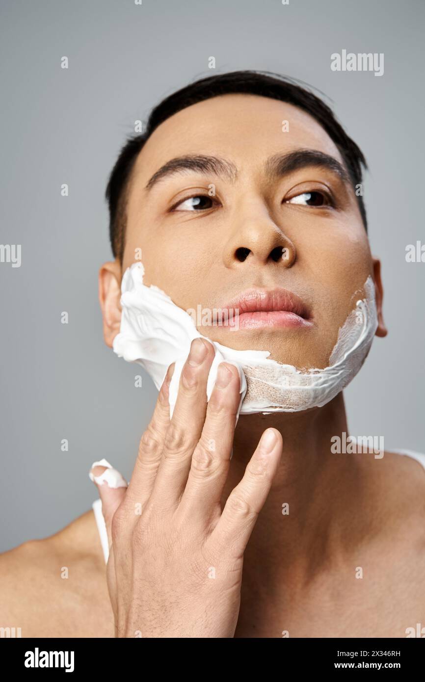 Handsome Asian man with shaving foam on face in a grey studio Stock Photo - Alamy