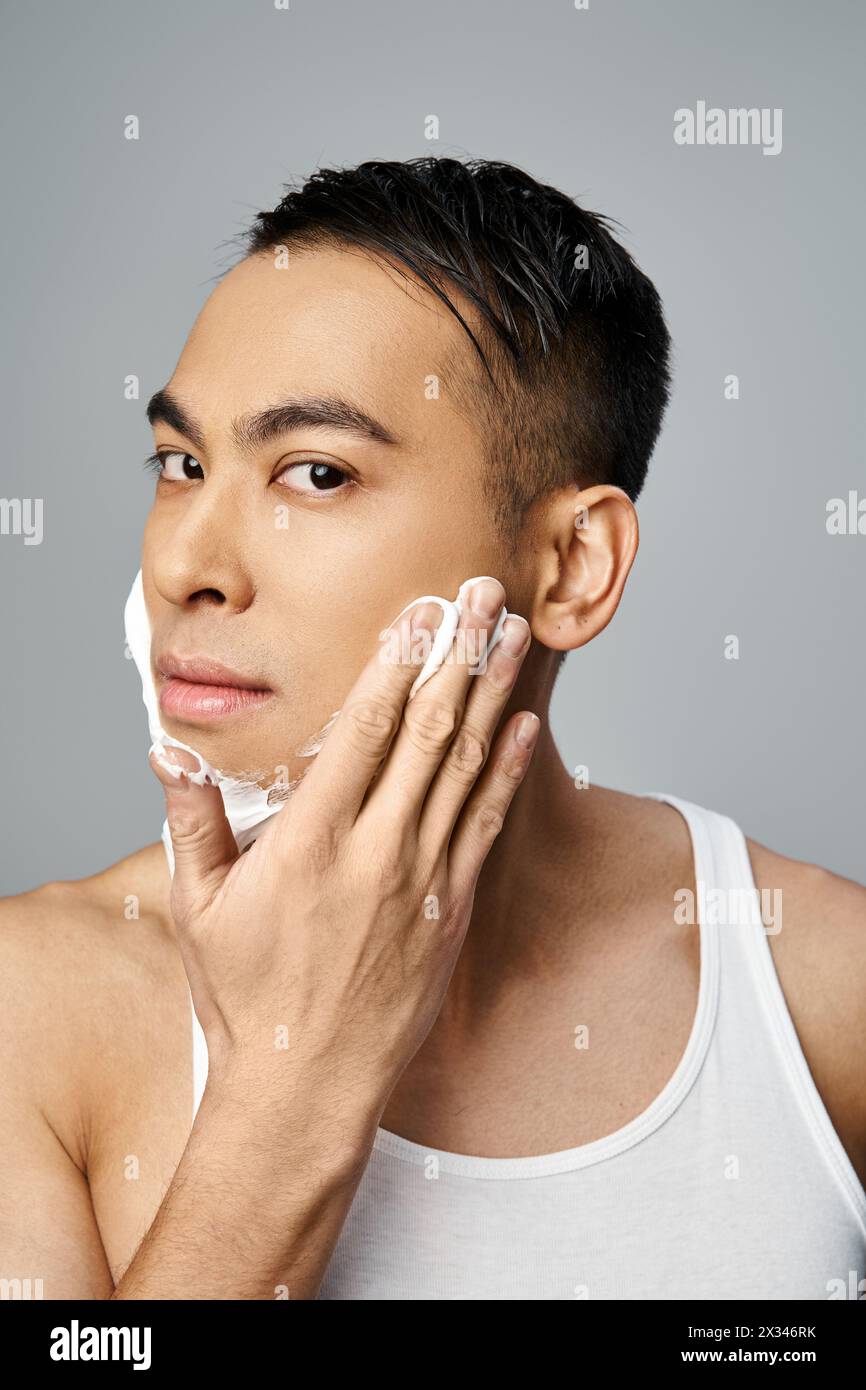 A handsome Asian man with shaving foam on his face in a grey studio Stock Photo - Alamy