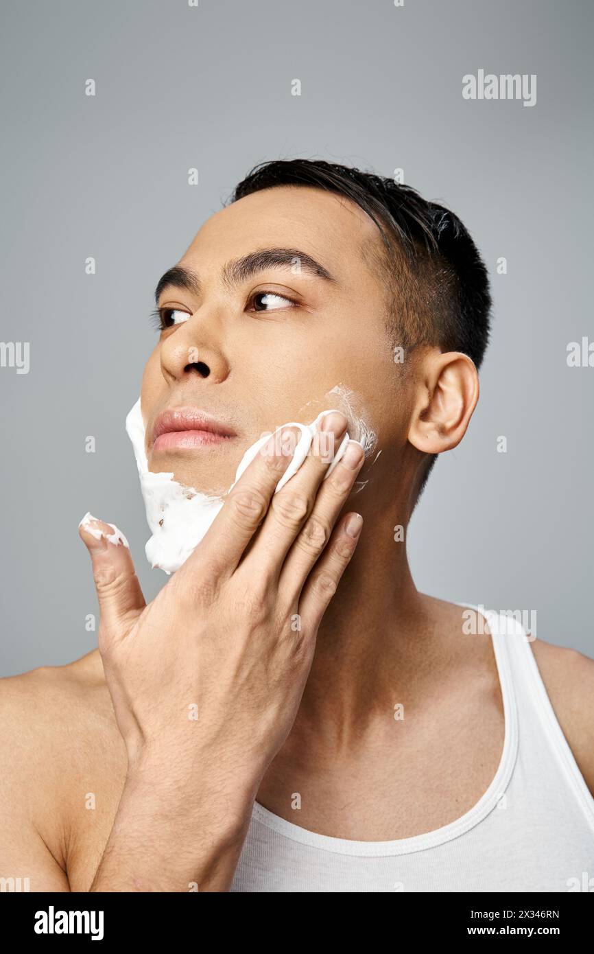 Handsome, Asian man with shaving foam on face, in a grey studio setting Stock Photo - Alamy