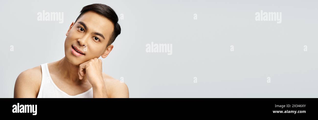 Handsome Asian man striking a pose in a grey studio setting while ...