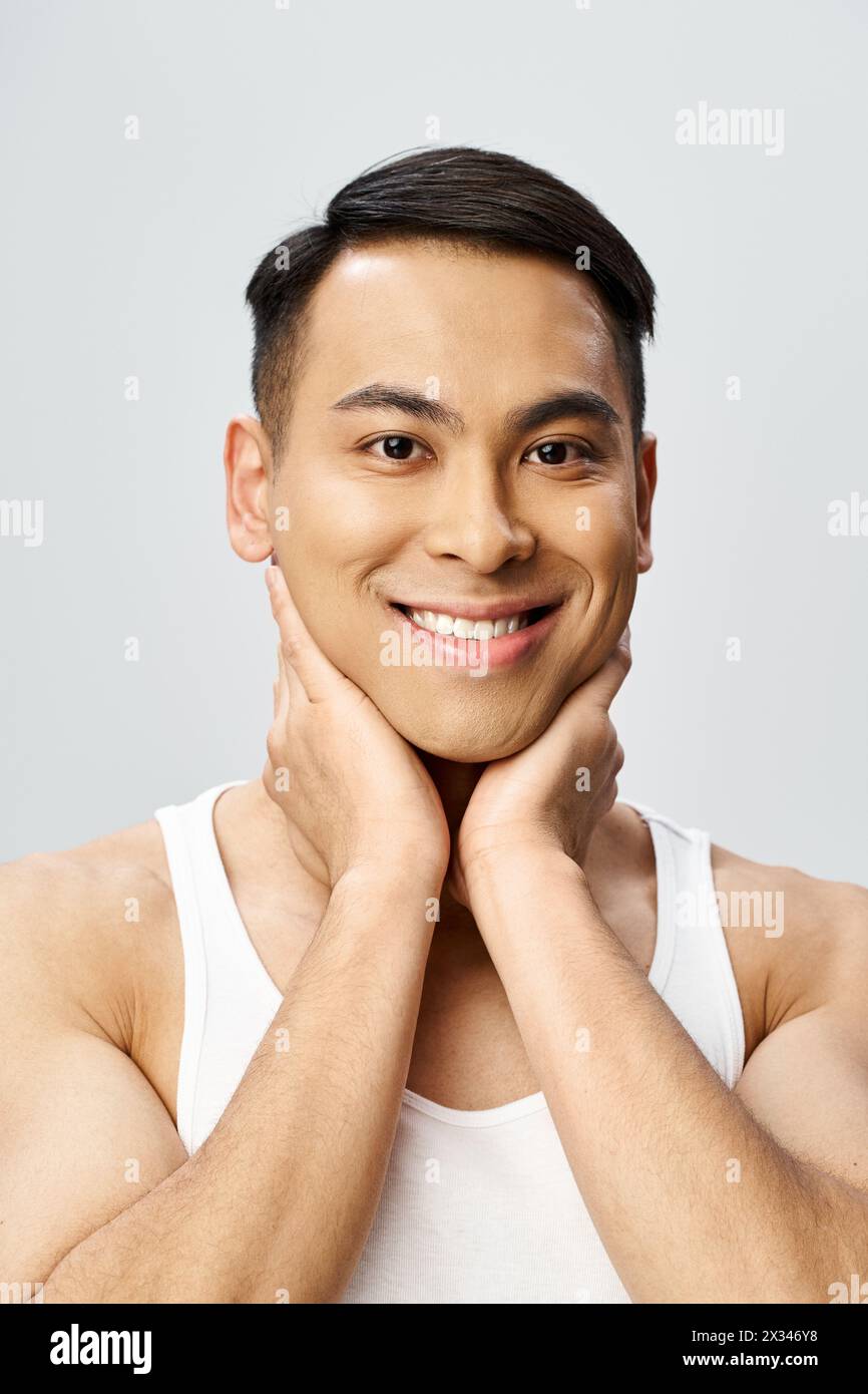 A handsome Asian man with a cheerful smile, hands resting on his chin ...