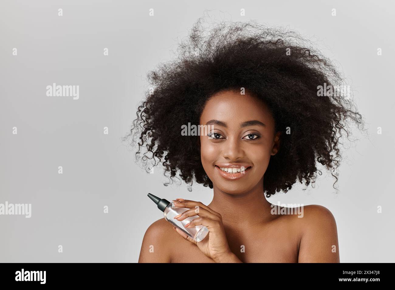 A stunning African American woman with a voluminous afro holds a bottle ...