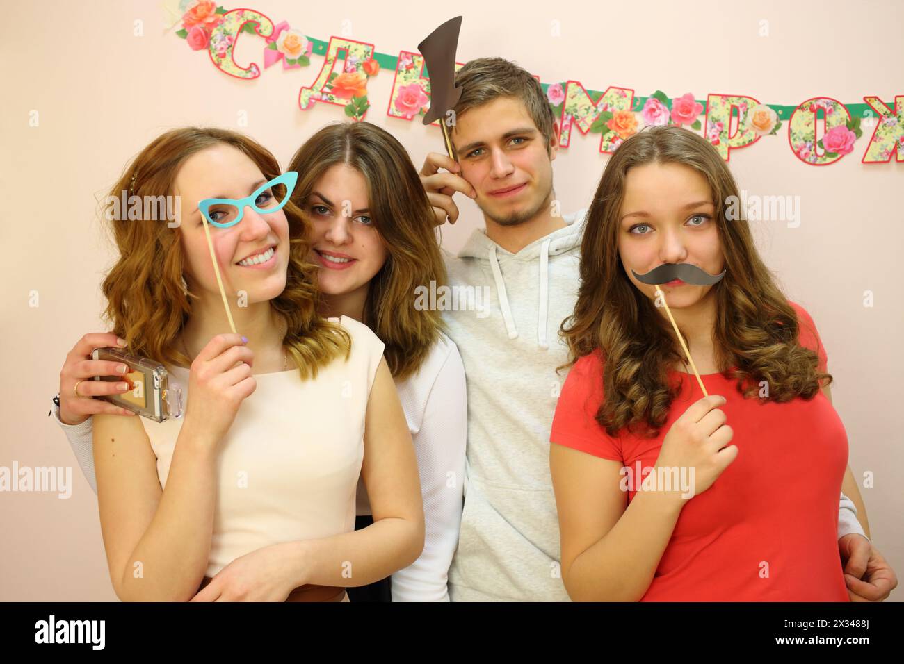 Portrait of a young man and three girls with the paper props near the ...