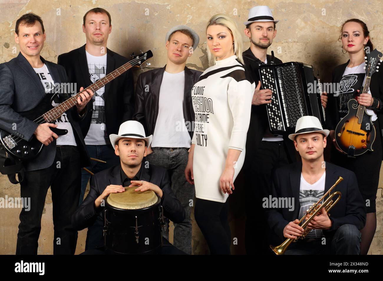 Music band of eight young people in white and black clothes pose in ...