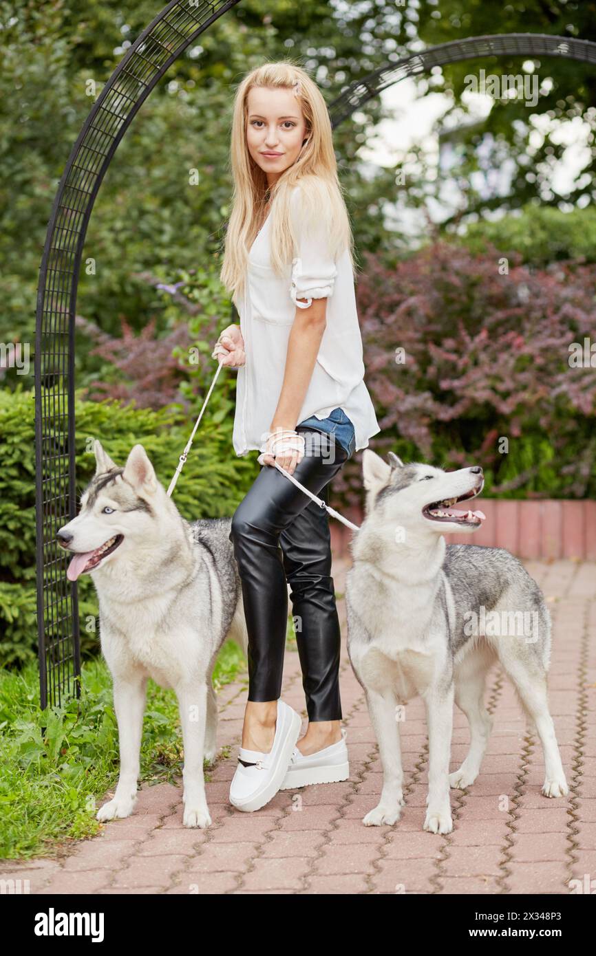 Young blond woman with two dogs Husky walks in summer park Stock Photo ...