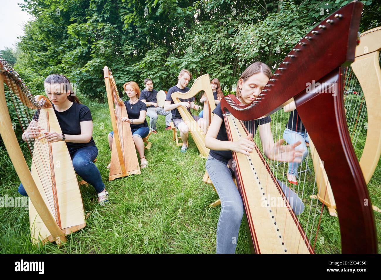 Ensemble of seven musicians play harps outdoors Stock Photo - Alamy